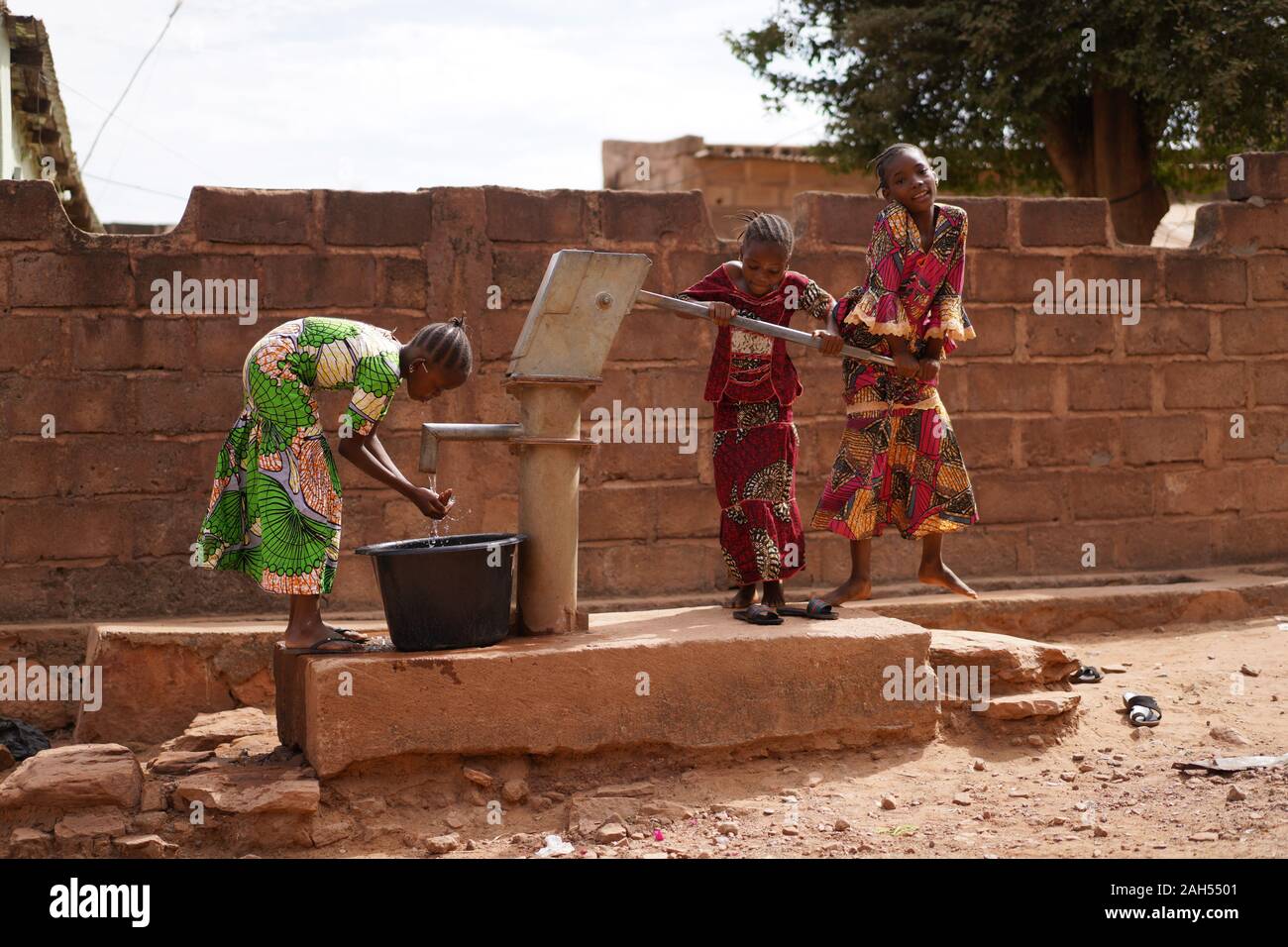 Three Small African Girls Happpily Managing A Borehole Hand Pump To ...