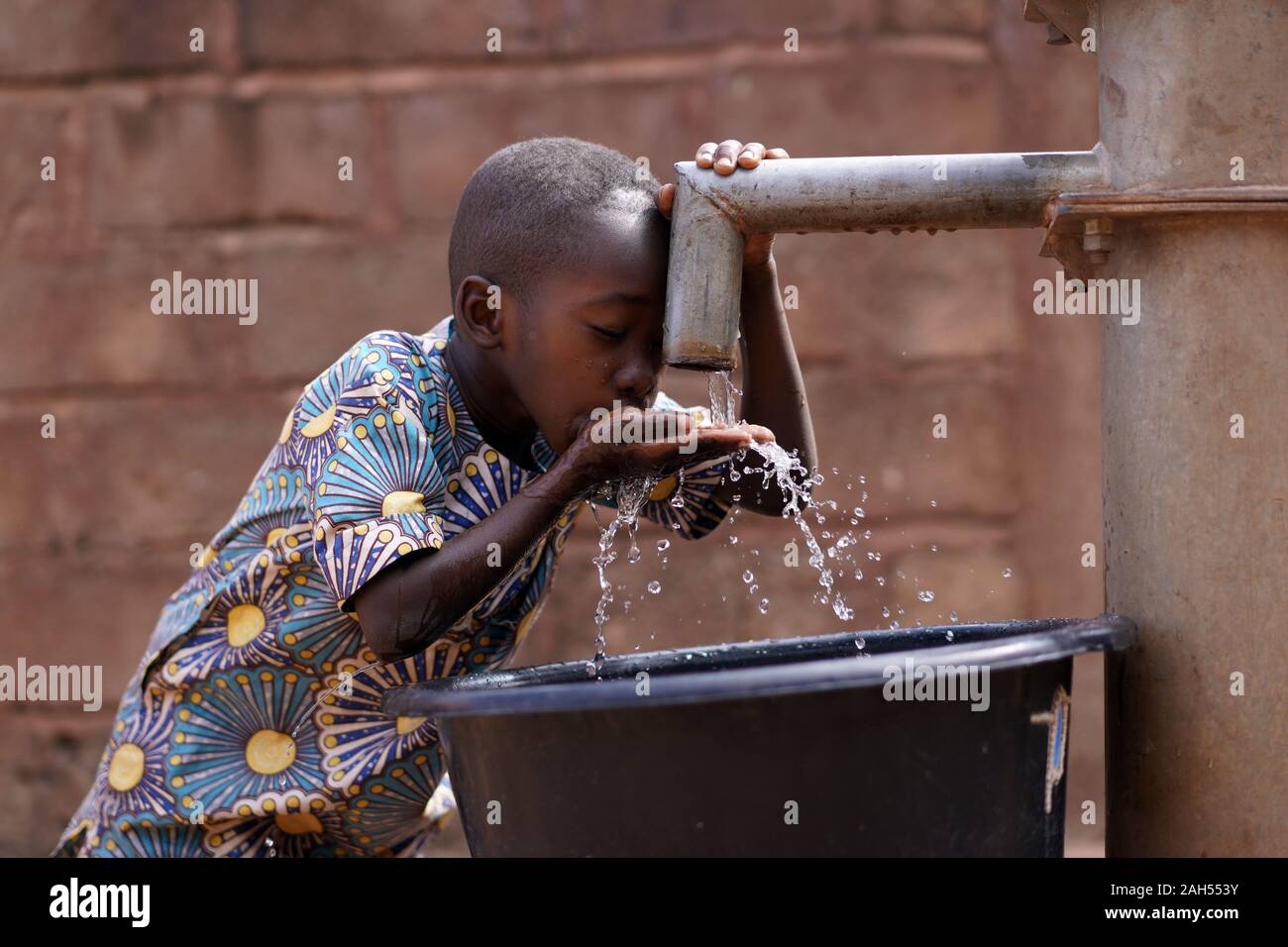Young African Boy Drinking Water From The Community Borehole Hand Pump ...