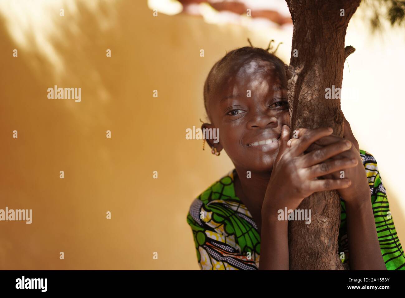Light Effects On A Smiling African Girl's Face Clinging To A Tree Trunk ...