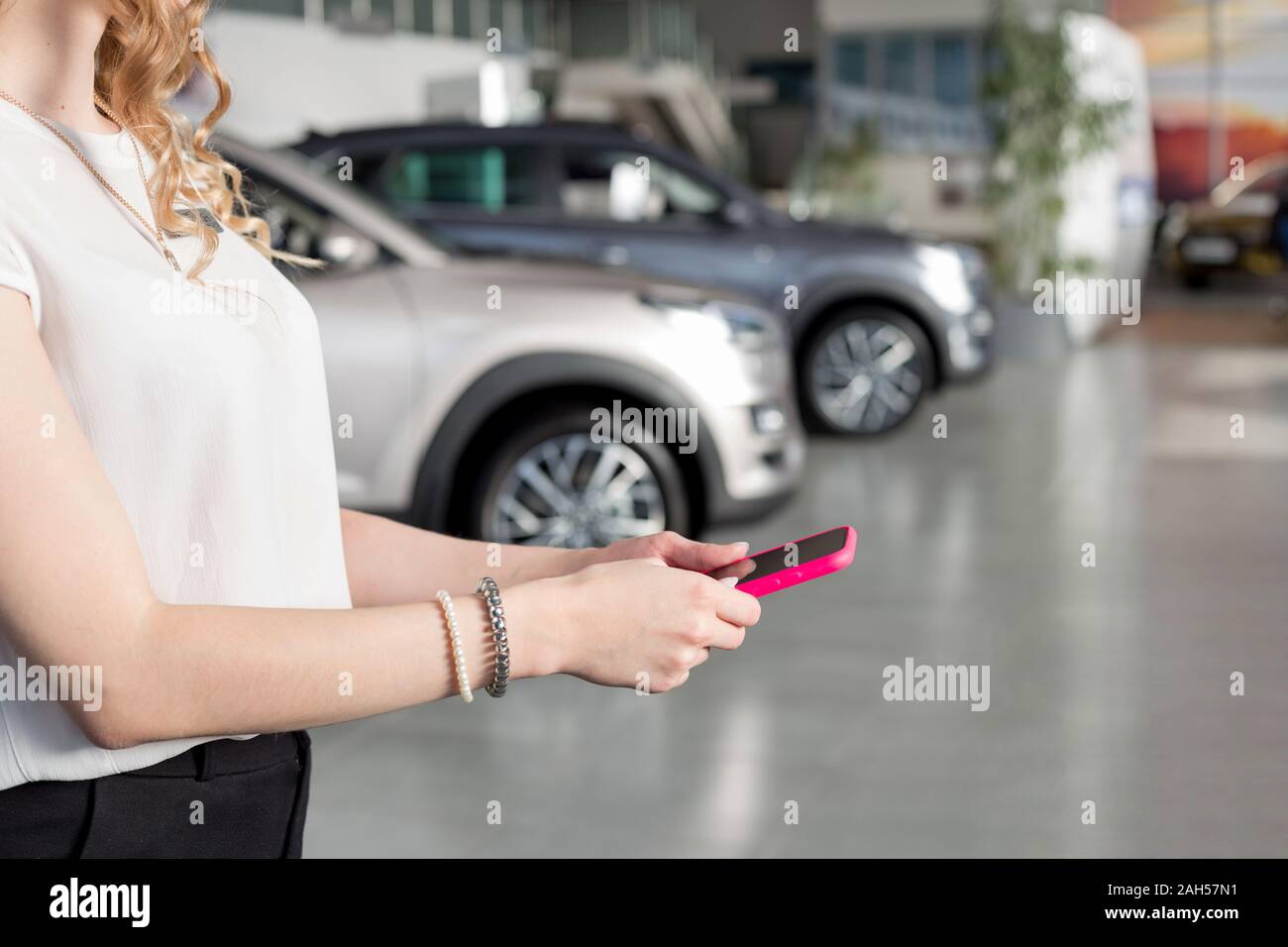 Woman dealer using mobile smart phone at dealer showroom. Modern ...