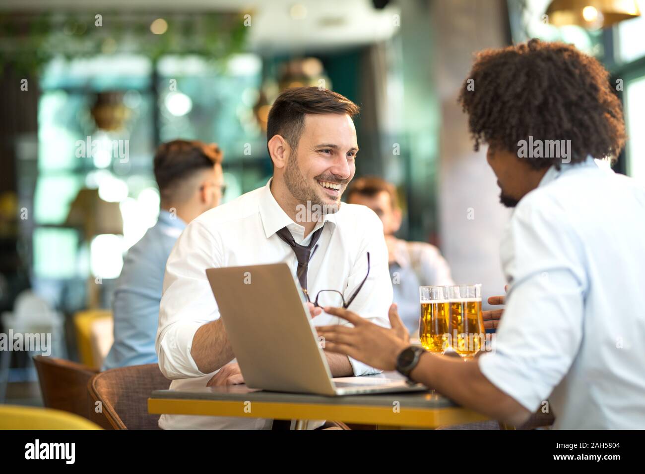 Two businessmen working on the go on a laptop together in a cafe Stock ...