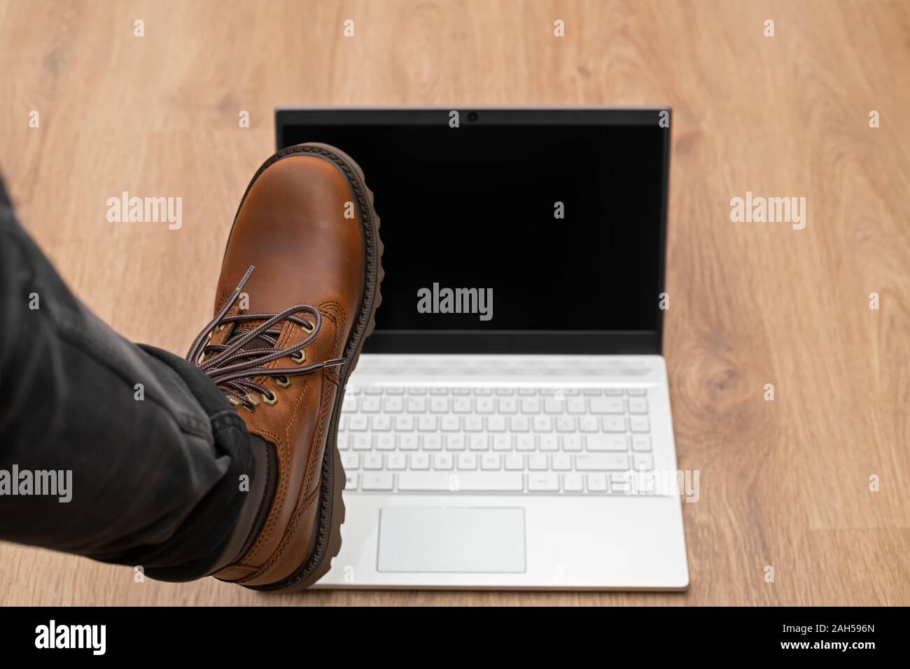 Frustrated man kicking a laptop with brown boots on office floor Stock ...