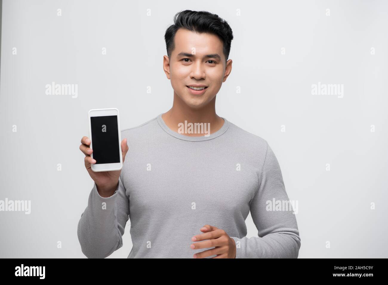 Happy smiling young Asian man showing mobile phone on white Stock Photo ...