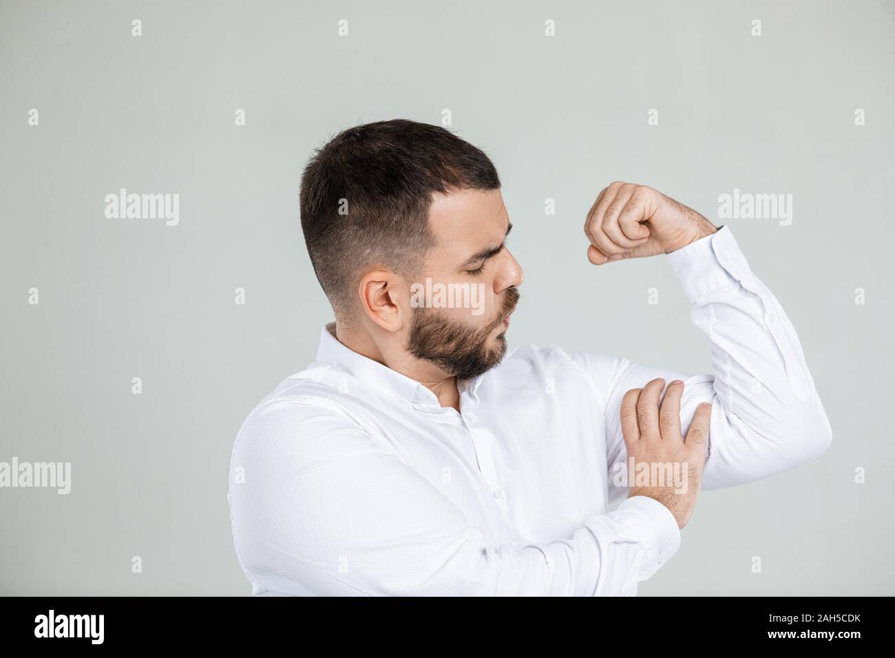 bearded muscular man shows biceps on gray background Stock Photo - Alamy