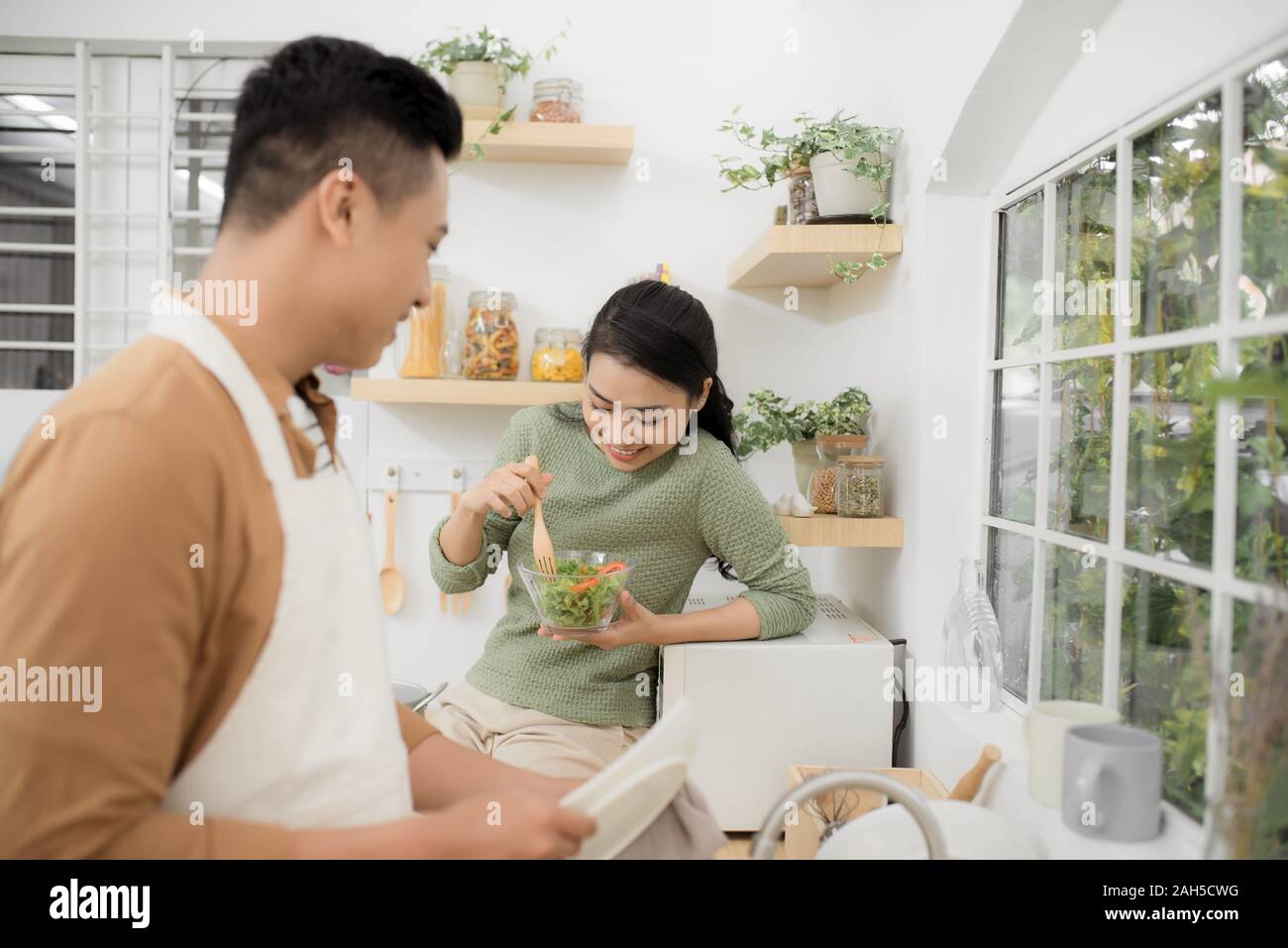 Loving woman feeding man while cooking dinner at kitchen Stock Photo ...