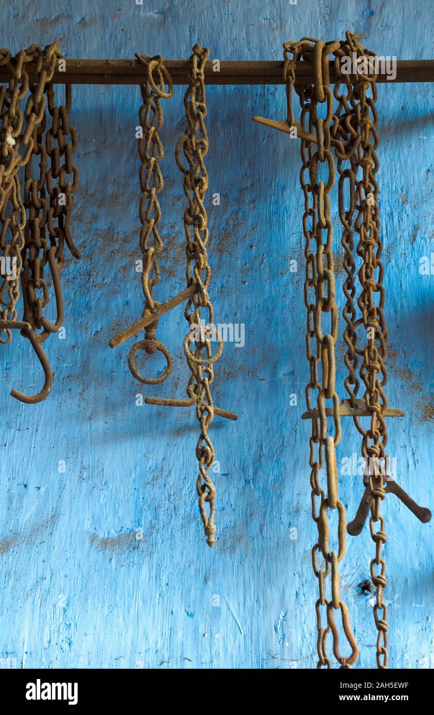 A close up view of many rusted chains and rings hanging on a wall ...