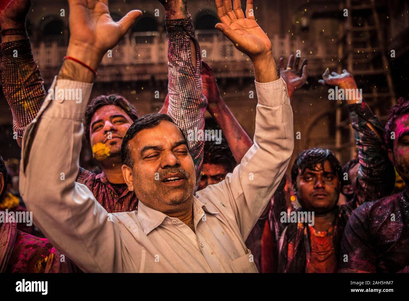 Man raising his arms in devotion during Holi celebrations inside Bankey ...