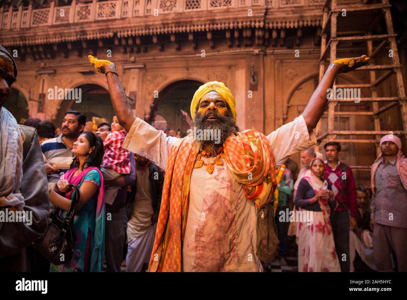 Man with painted face raising his arms during Holi celebrations inside ...