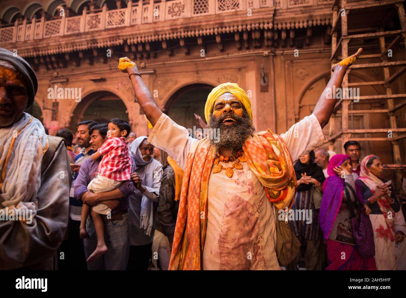 Man with painted face raising his arms during Holi celebrations inside ...