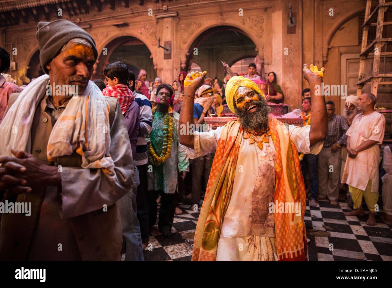 Man with painted face raising his arms during Holi celebrations inside ...