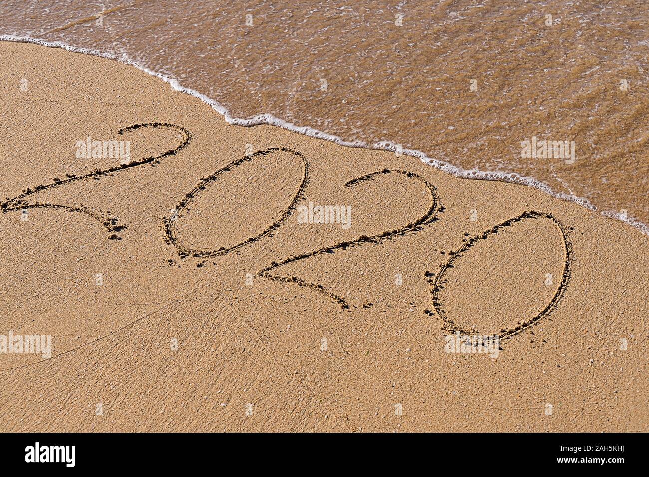 Numbers 2020 hand written at sandy seashore beach. Lettering with 2020 ...