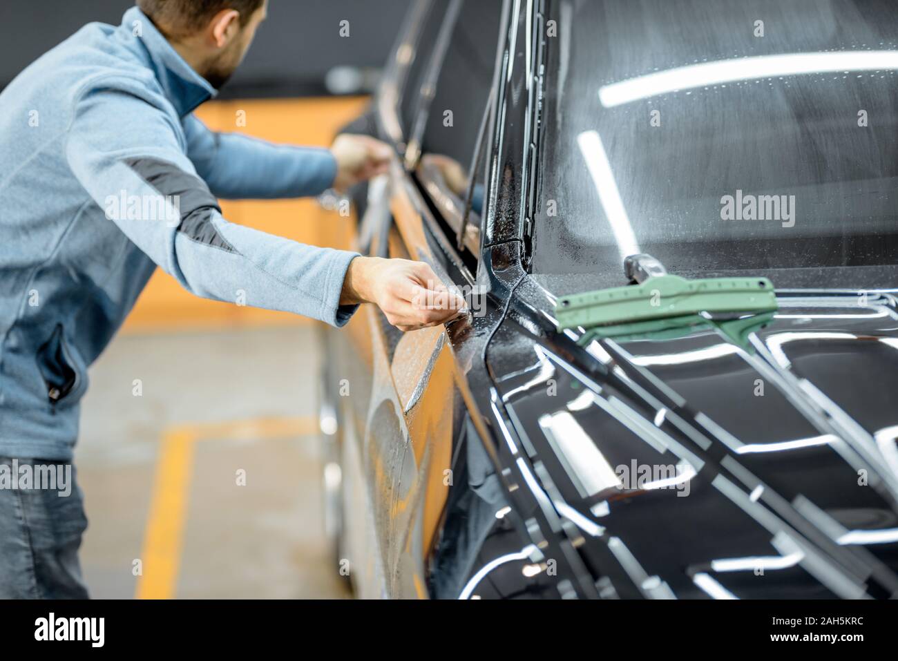 Car service worker sticking anti-gravel film on a car body for ...