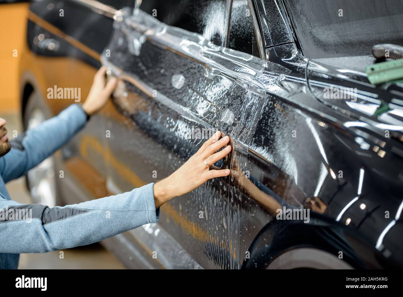 Car service worker sticking anti-gravel film on a car body for ...