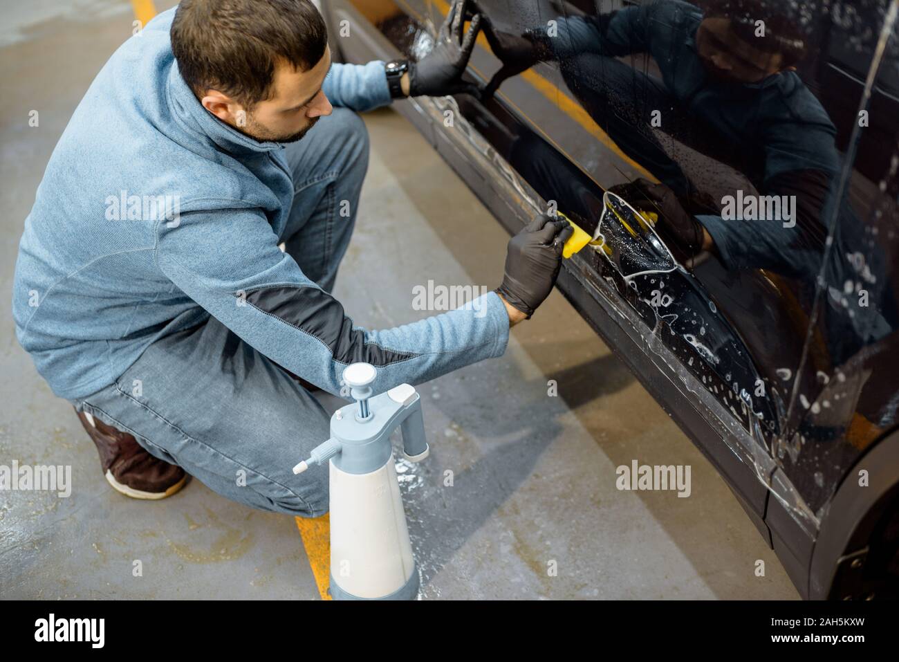 Car service worker sticking anti-gravel film on a car body with ...