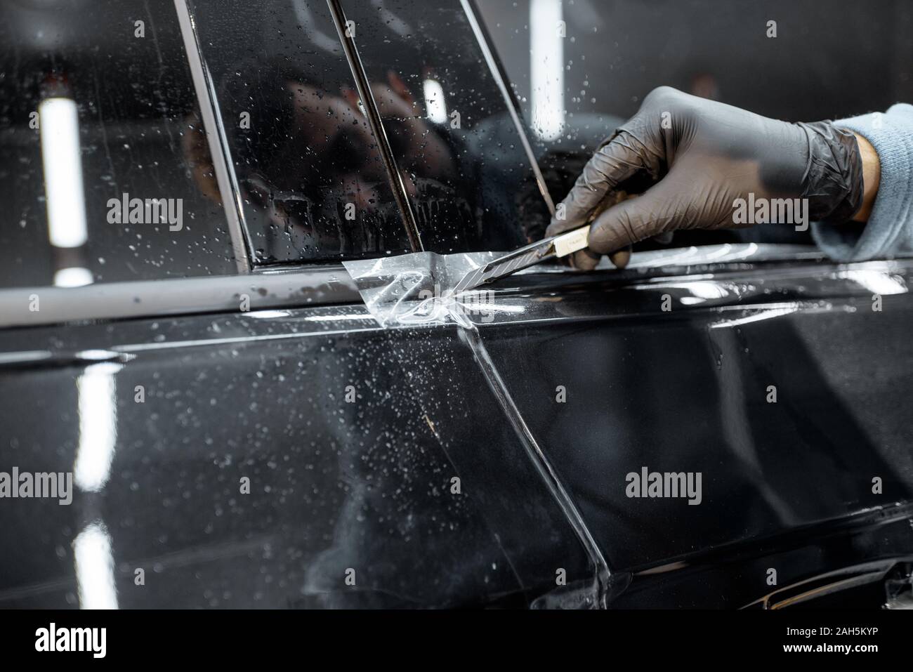 Worker trimming with cutter remains of a protective film, sticking it ...