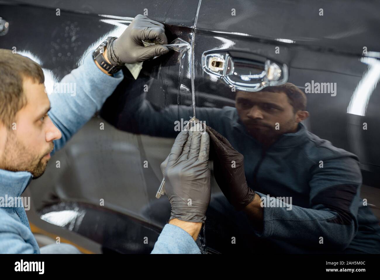 Worker trimming with cutter remains of a protective film, sticking it ...