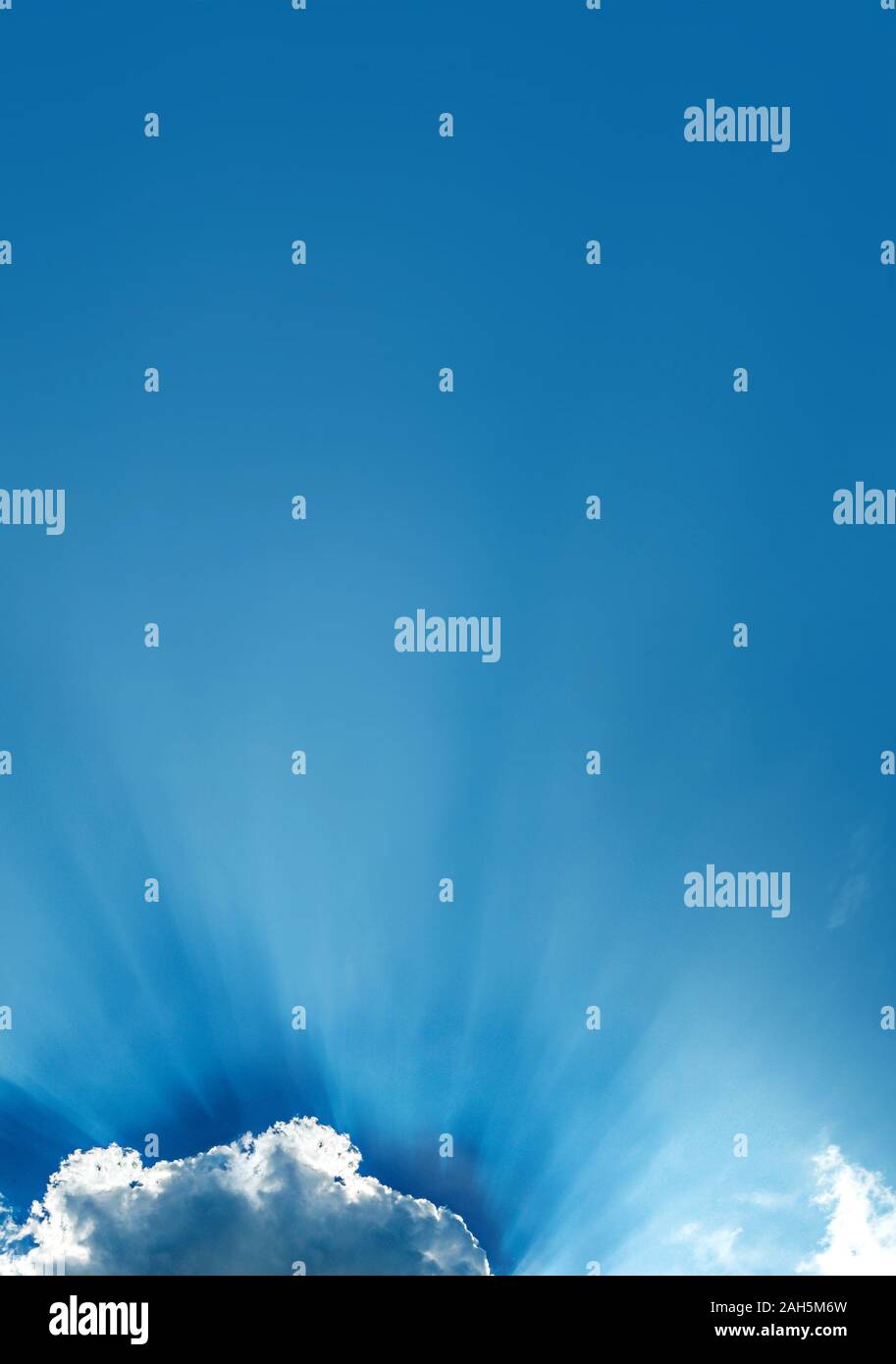 Sun rays bursting through clouds in a blue sky Stock Photo - Alamy