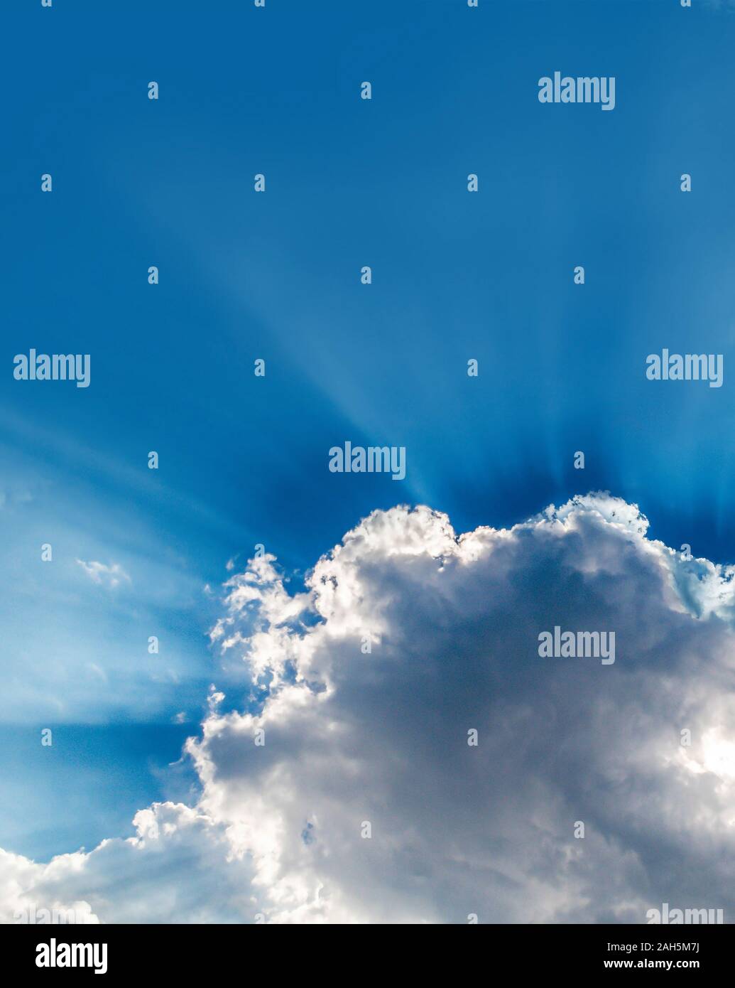 Sun rays bursting through clouds in a blue sky Stock Photo - Alamy