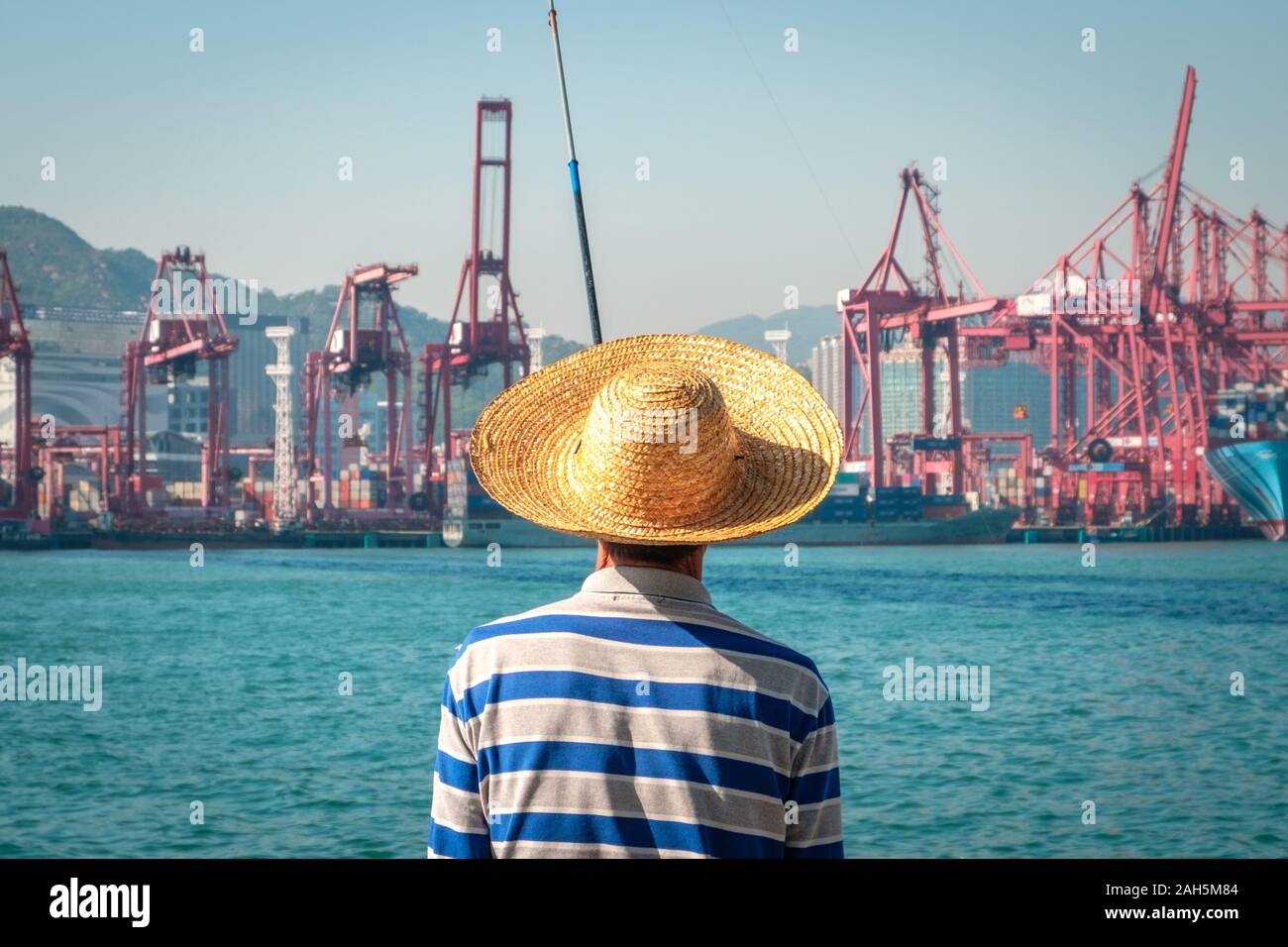 Fisher man with fishing rod from behind near container ship and freight ...