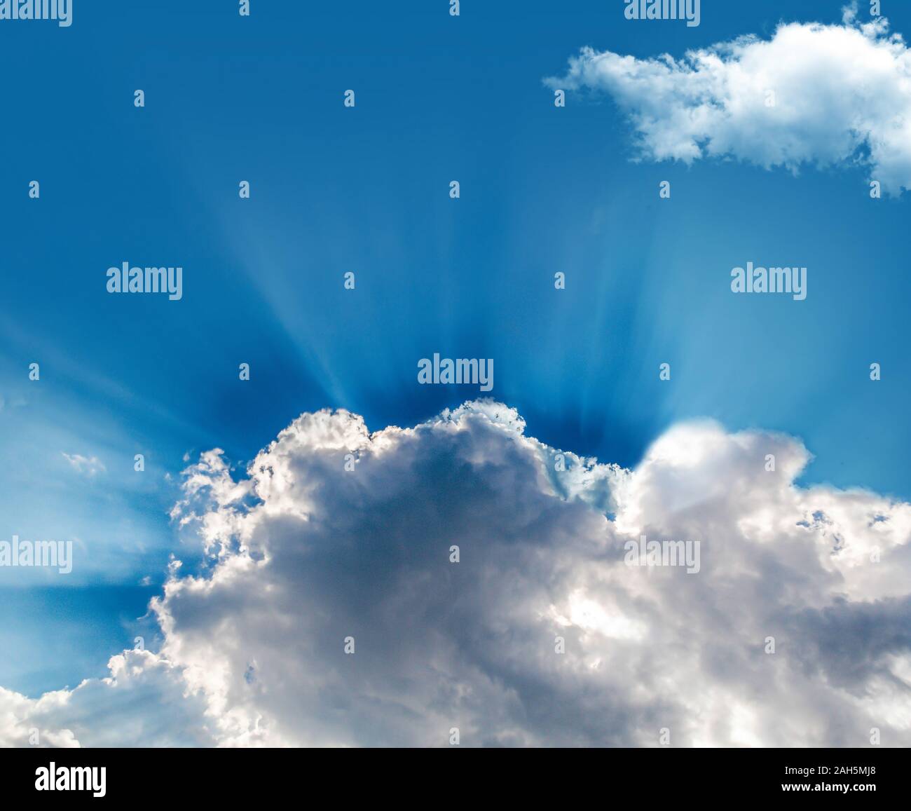 Sun rays bursting through clouds in a blue sky Stock Photo - Alamy