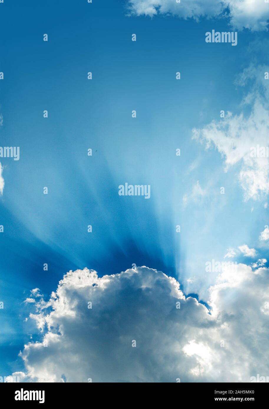 Sun rays bursting through clouds in a blue sky Stock Photo - Alamy