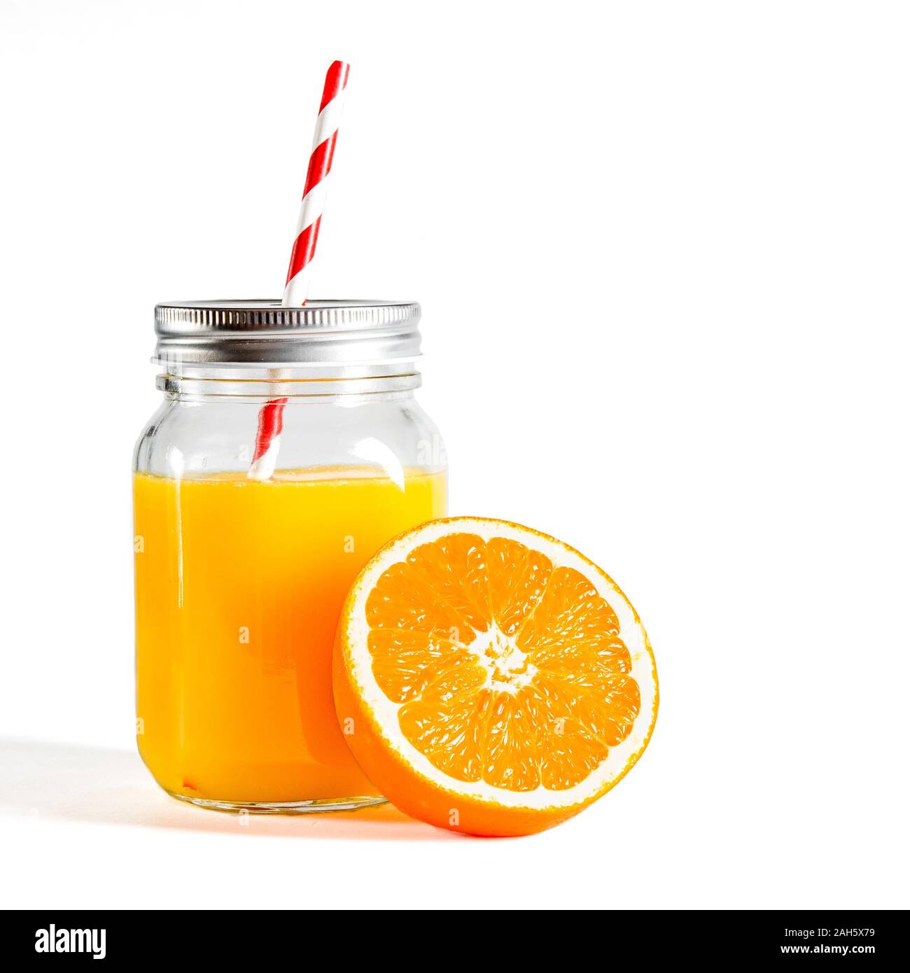 Glass jar with a tube with freshly squeezed orange juice stands on a ...