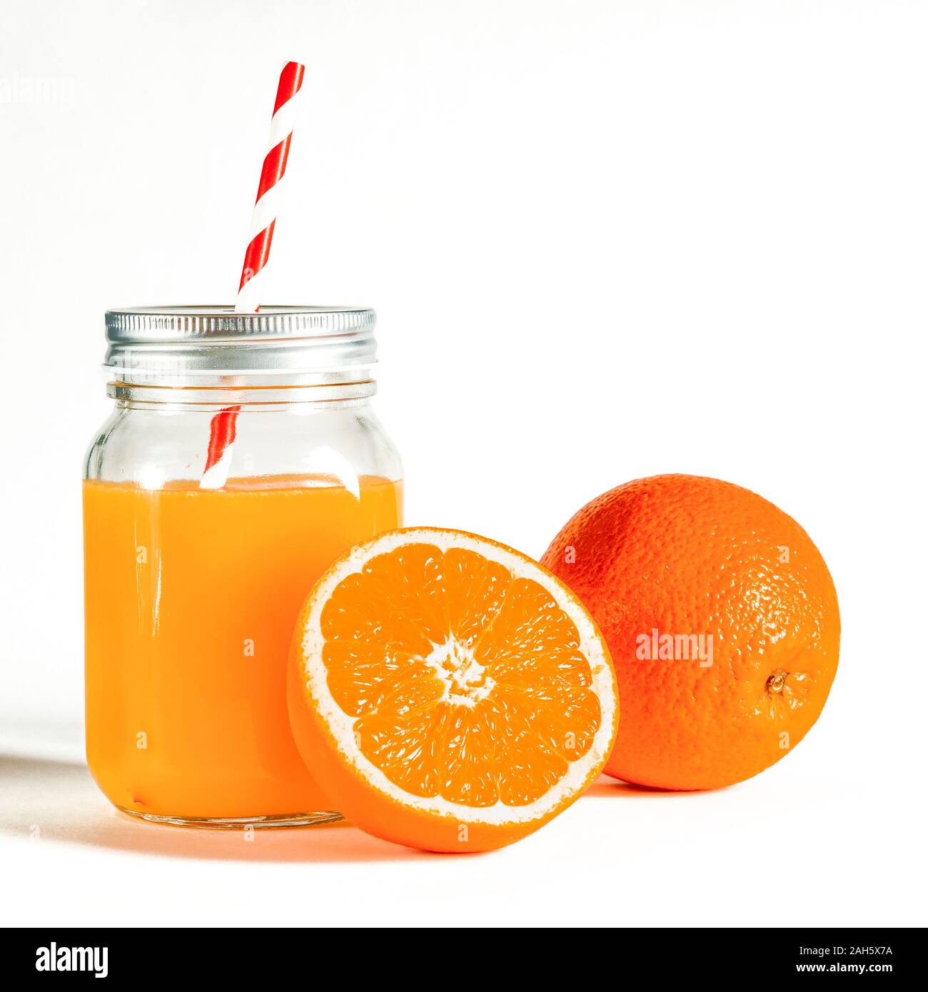 Glass jar with a tube with freshly squeezed orange juice stands on a ...