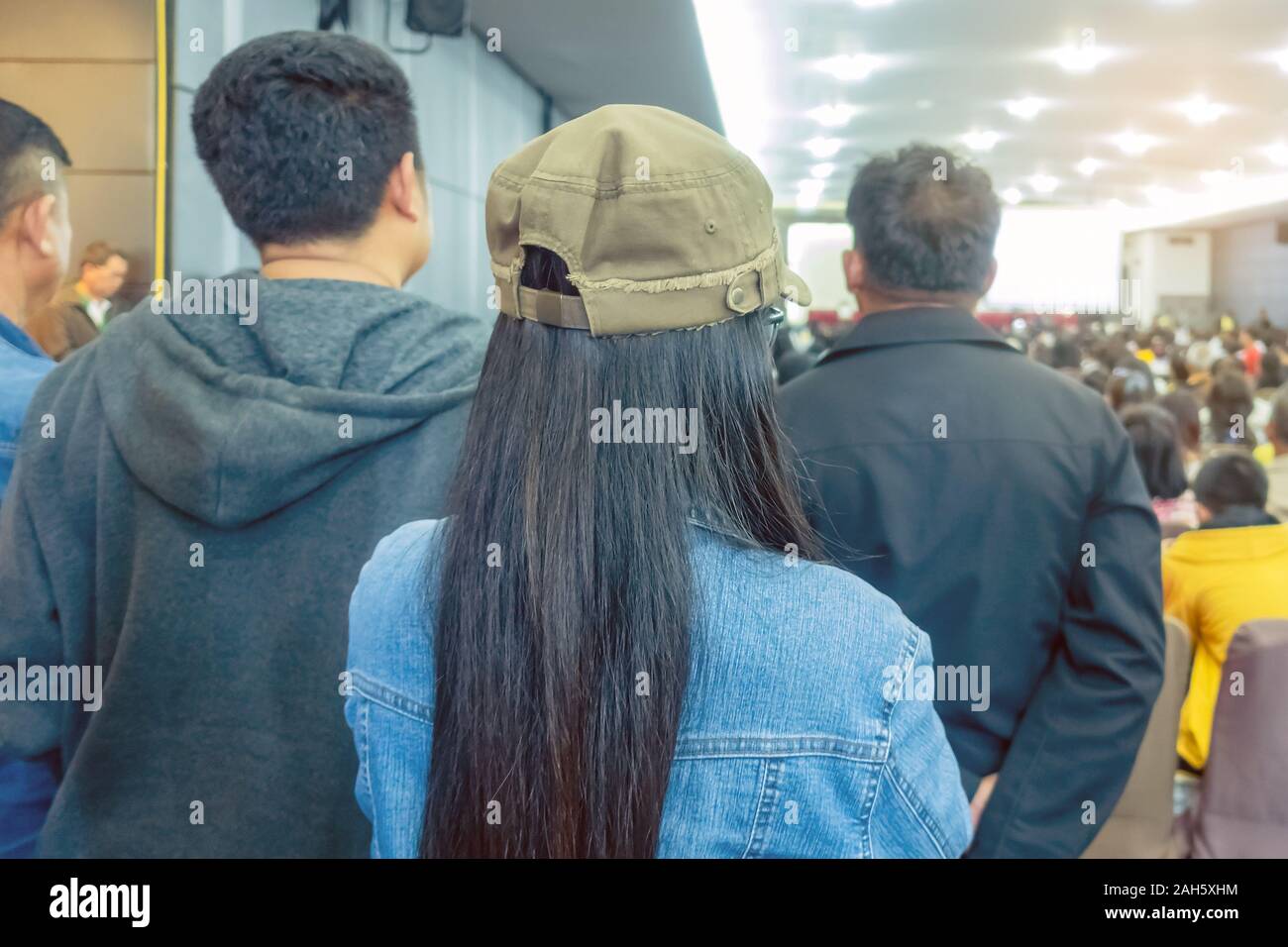 Backside view of spectators standing in a gathering in the back of ...