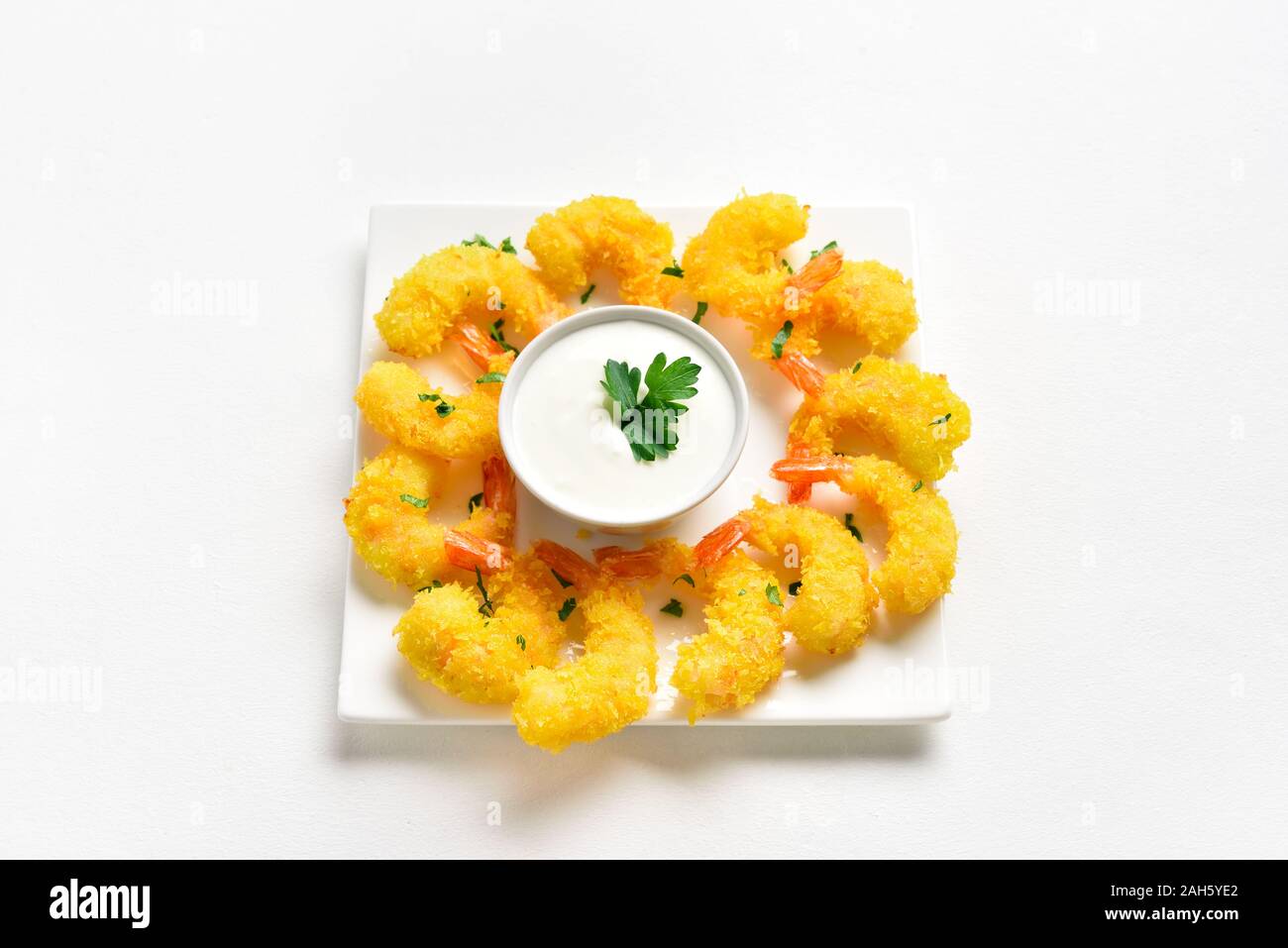 Deep fried breaded prawn with sauce on white plate over light stone ...