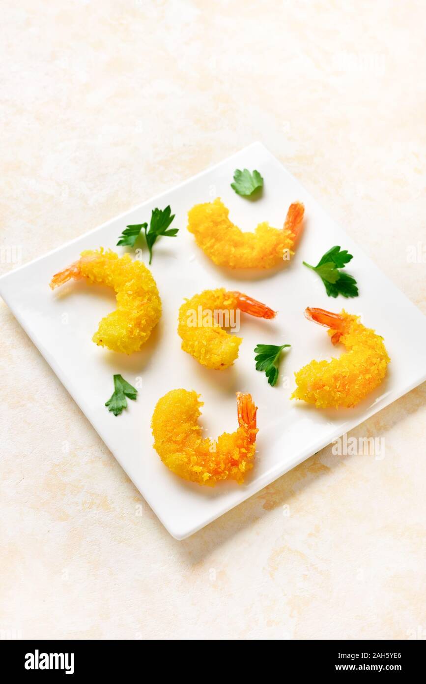 Deep fried breaded prawn on white plate over light stone background ...