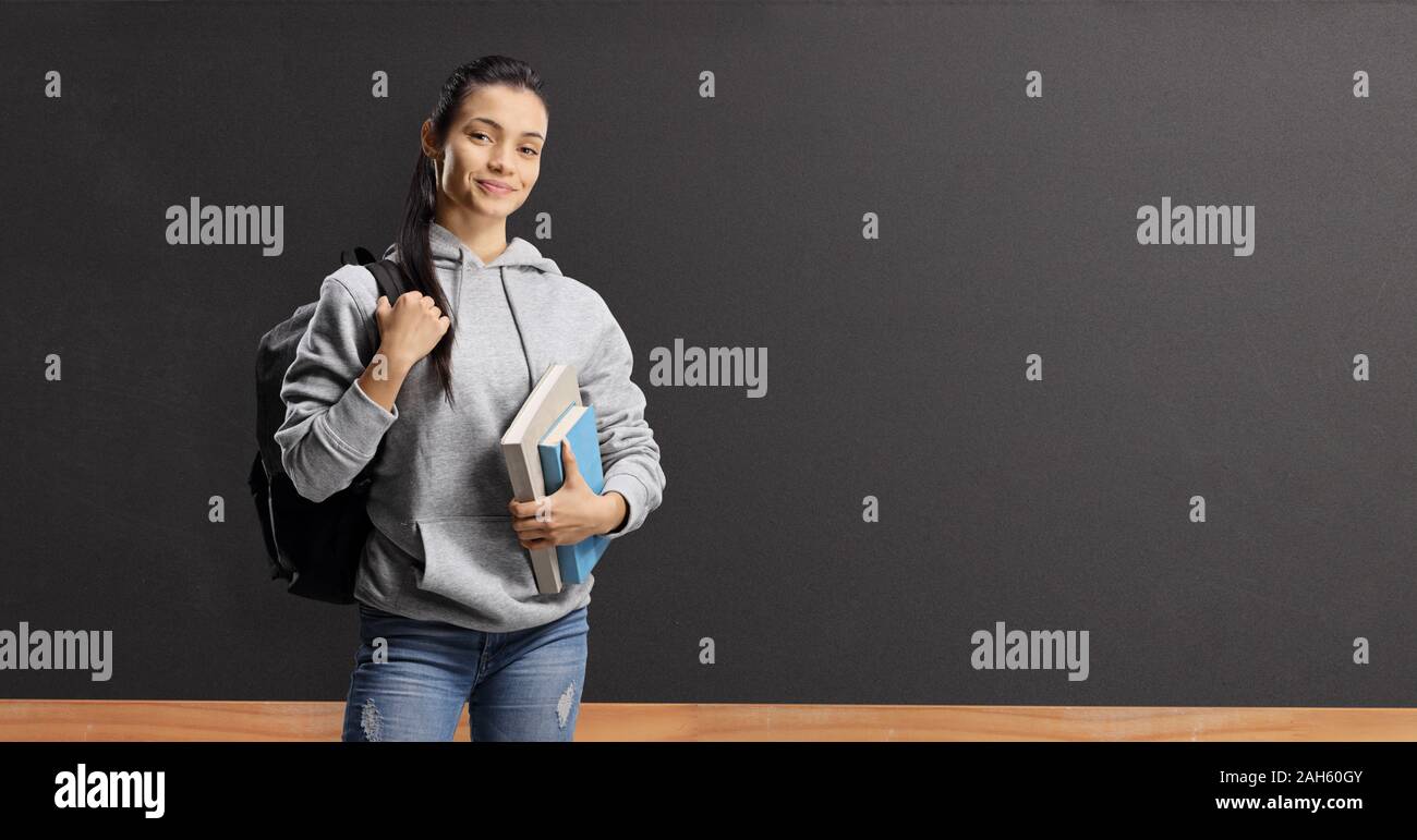 Female student with books standing in front of a blackboard Stock Photo ...