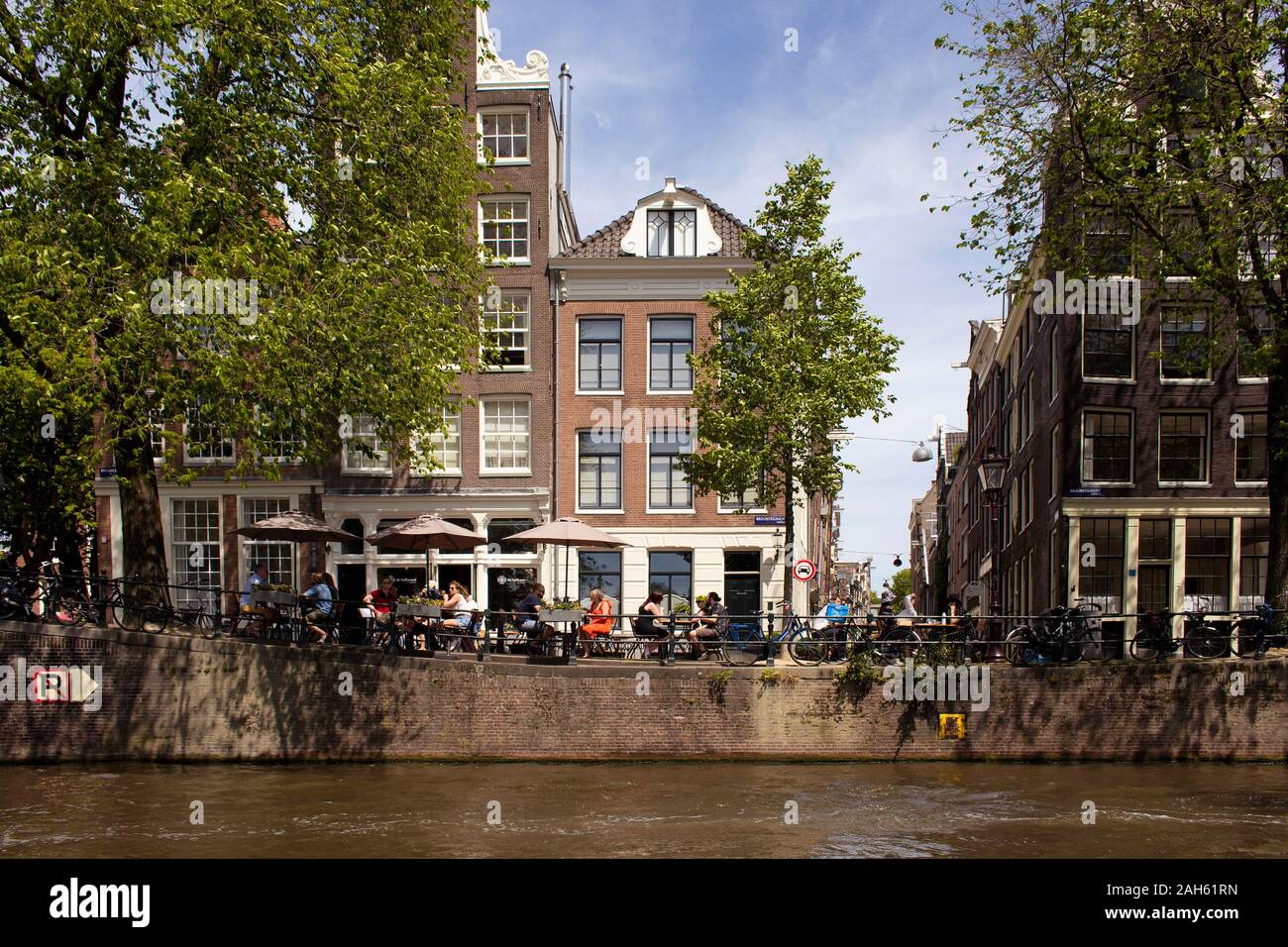View of people hanging out by canal at a cafe, trees, historical and ...