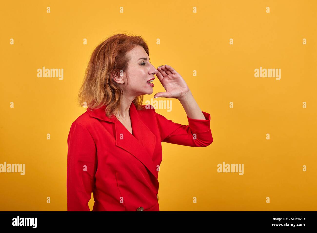 Caucasian woman staying sideways, keeping hand near face, scream ...