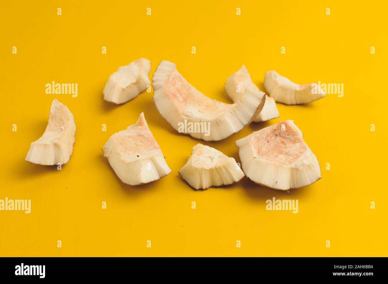 ugly organic broken rotten coconut on bright yellow background. pieces ...