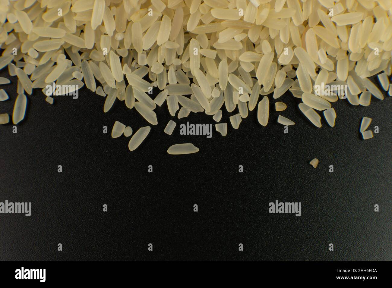 long white polished rice on a black background Stock Photo - Alamy