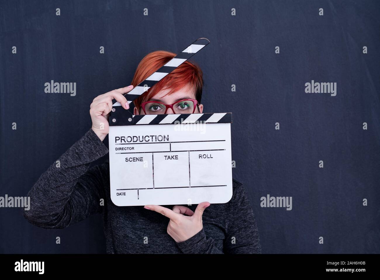 redhead woman on black chalkboard holding movie clapper cinema concept ...