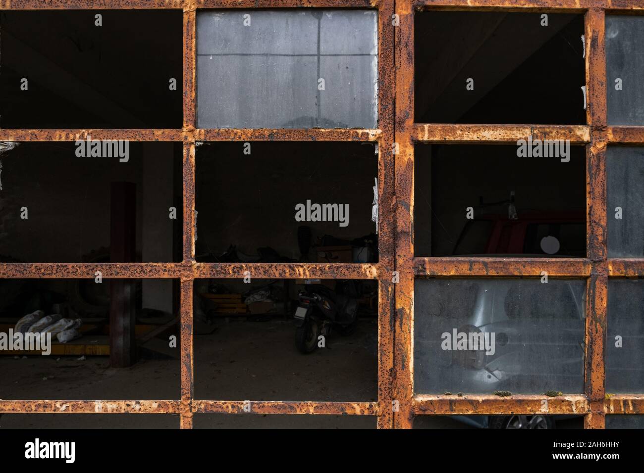 The broken windows and rusting frame of a door leading into a garage ...