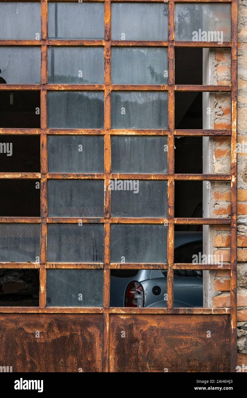 The broken windows and rusting frame of a door leading into a garage ...