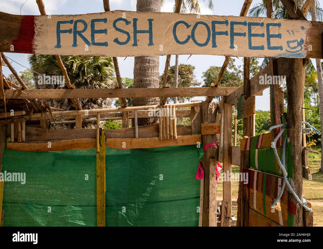 A rustic hand painted wooden sign at the beach advertising fresh coffee ...