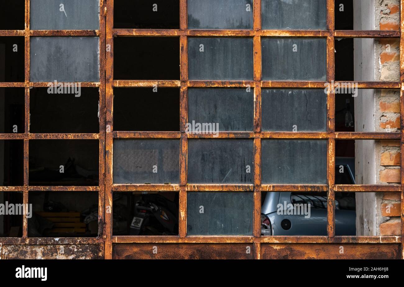 The broken windows and rusting frame of a door leading into a garage ...