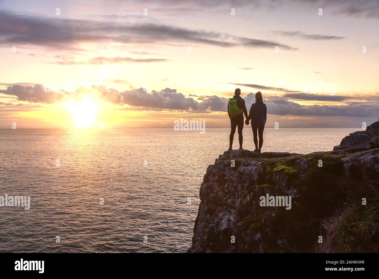 Adventurous couple holding hands and standing on a rocky cliff Stock ...