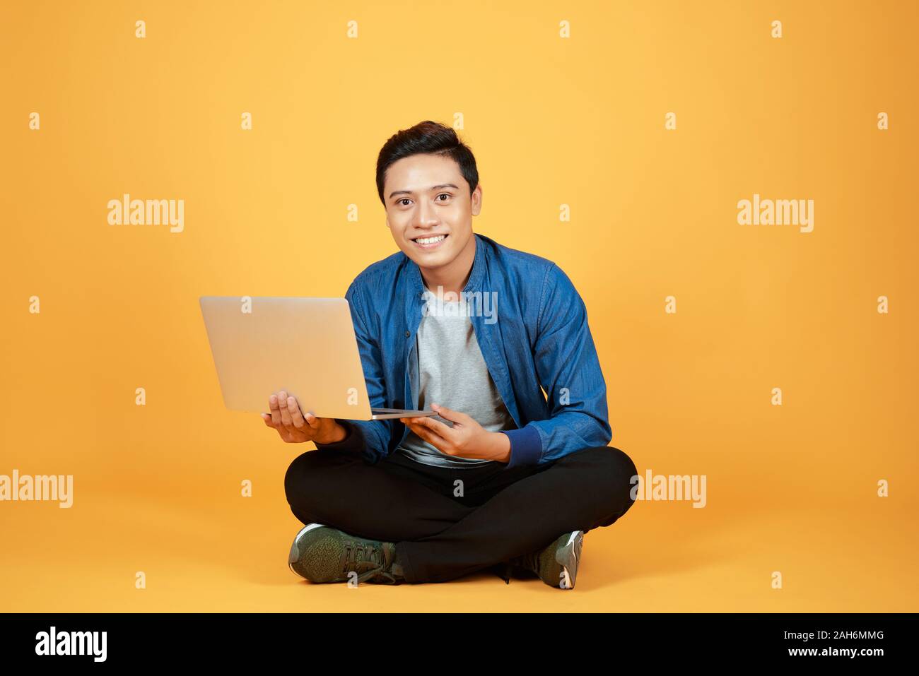 portrait of handsome asian man smiling while using computer laptop ...