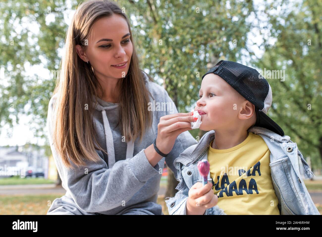 mother son, eat ice cream, wipe lips and face of child with napkin ...