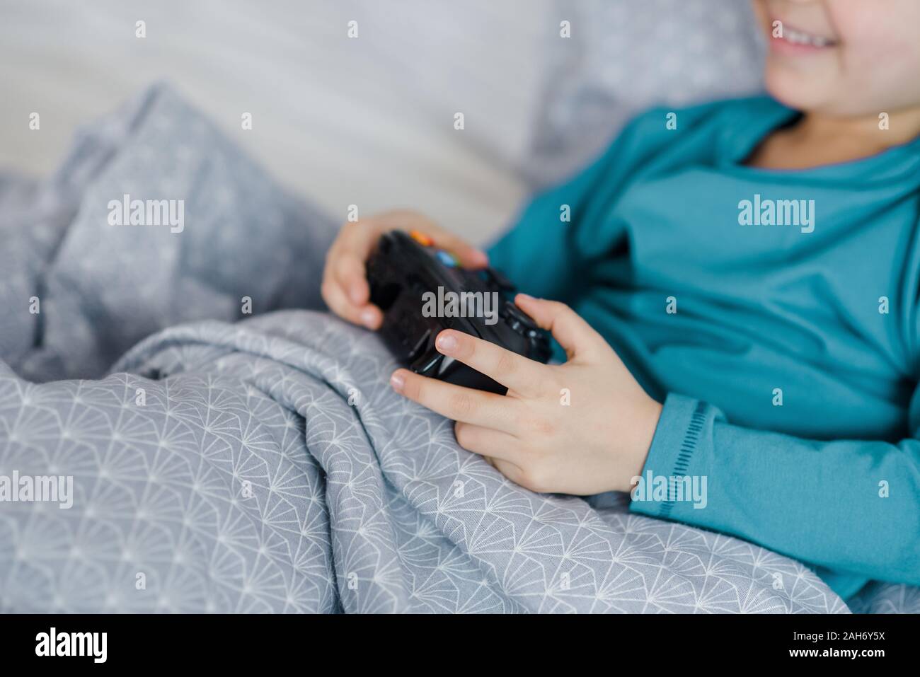 Close up of child hands playing video game at home. kid in bed wih ...