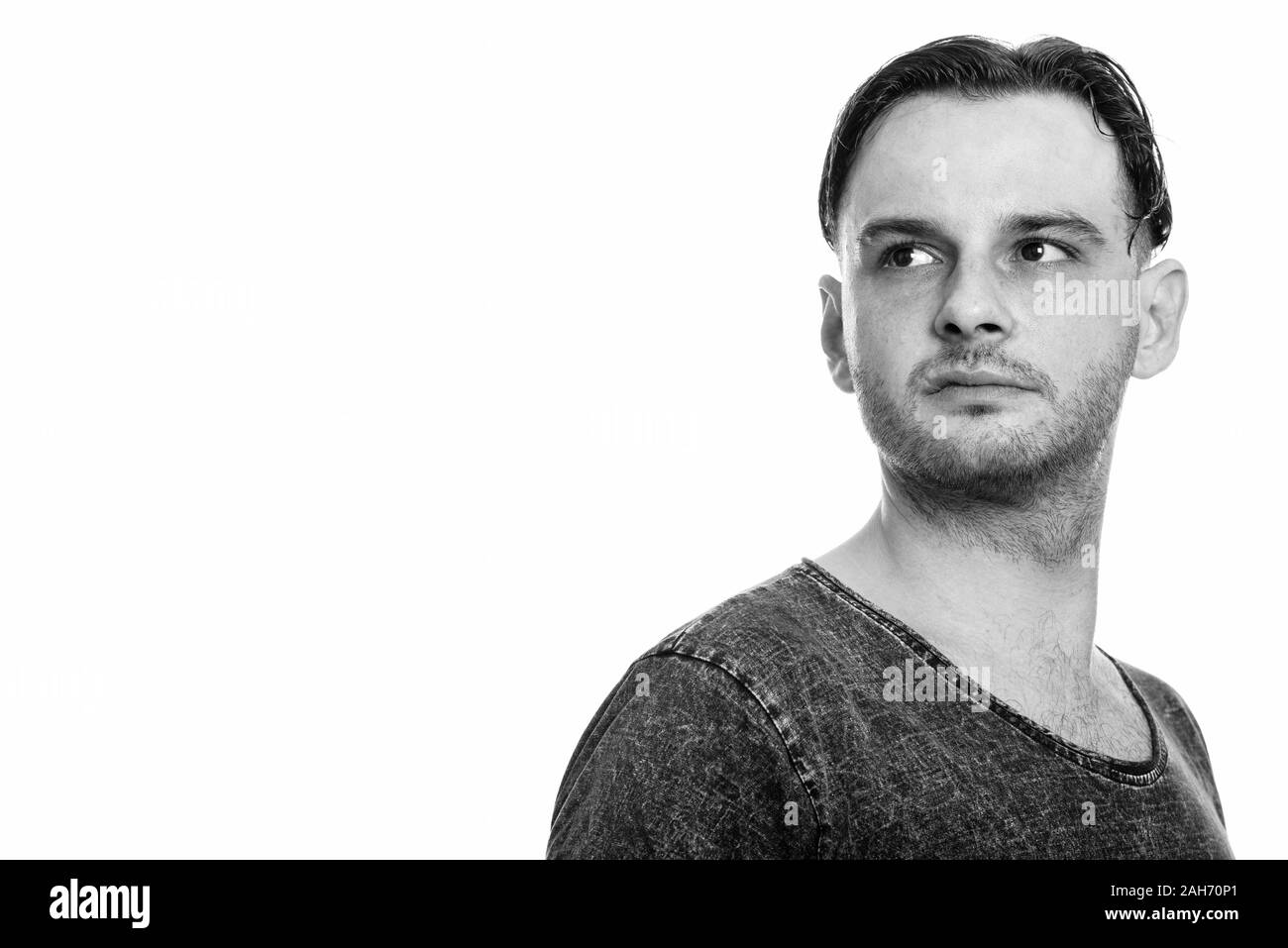Studio shot of young man looking back while thinking Stock Photo - Alamy