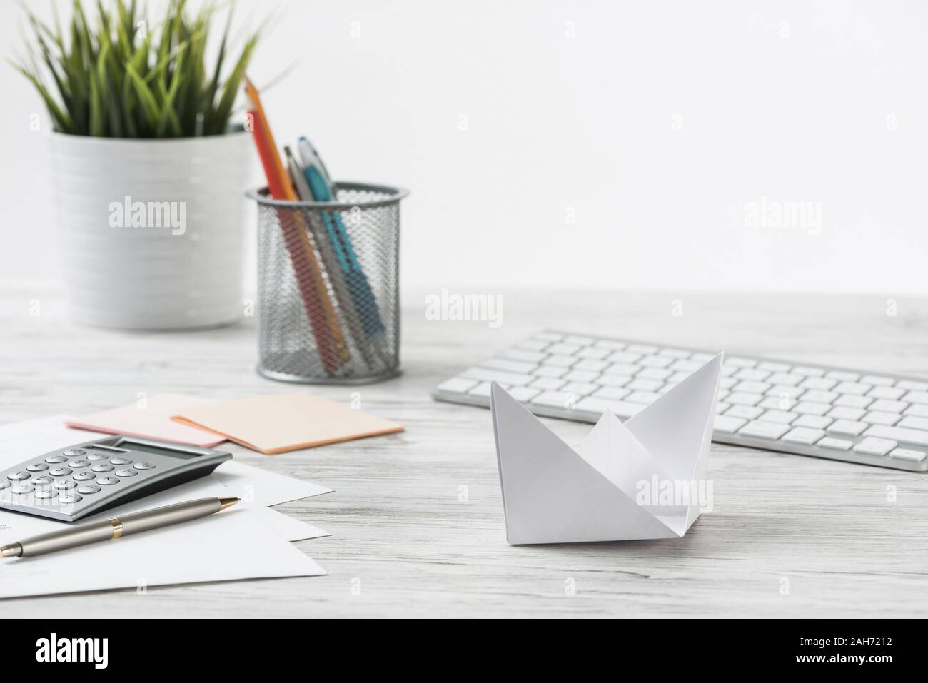Wooden office desk with white origami boat. Professional invest ...
