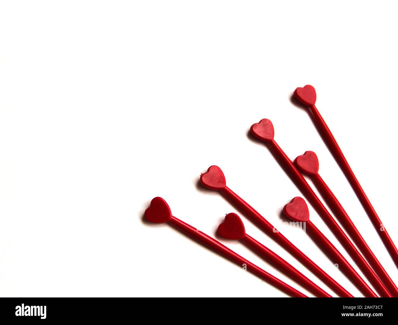 Red plastic sticks for canapes with a heart on a white isolated ...