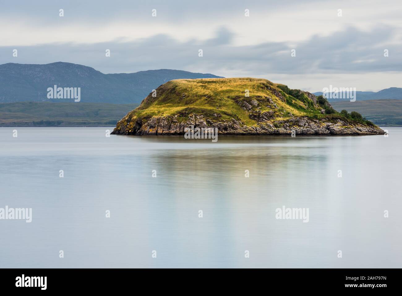 A small rocky island covered with green grass in a scottish lake with ...
