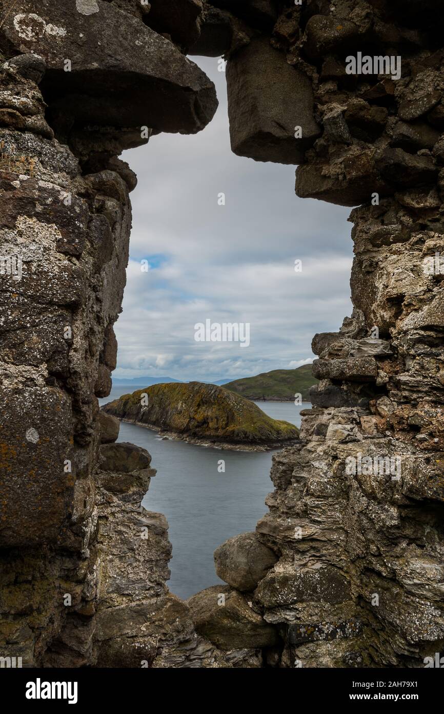 Through an opening on a rock wall can be seen the sea and a small ...