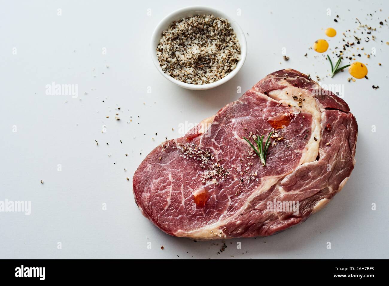 Portion of fatty marbled raw beef steak with spice rub and herbs on a ...